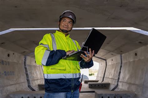 대형 건축 프로젝트 현장에서 일하는 아시아 엔지니어 기술설계 건축 용지 및 수송 건축 프로젝트를 위한 옥외 팀 45 49세에