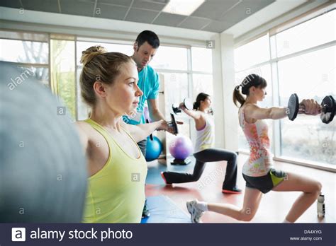 Full Length Of Instructor With Fitness Class Performing Step Aerobics Exercise In Gym Stock