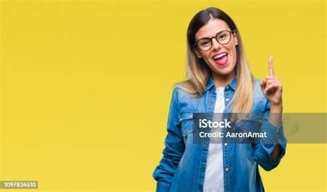 성공적인 아이디어를 고립 된 배경 가리키는 손가락에 안경을 착용 하는 동안 젊은 아름 다운 여자 종료 하 고 행복 번호 하나입니다 손가락에 대한 스톡 사진 및 기타 이미지