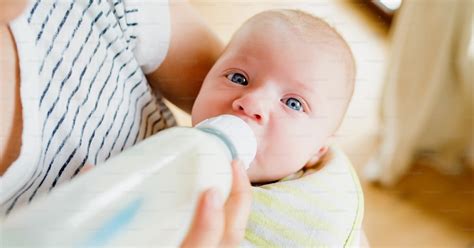 알아볼 수 없는 어머니가 아기 아들을 팔에 안고 병에서 우유를 먹이는 모습을 클로즈업합니다 사진 Unsplash의 작다 이미지