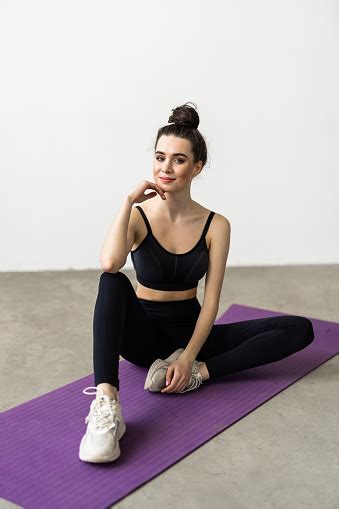 미소 짓는 아름다운 몸매 여성은 로프트 스튜디오에서 스트레칭 운동을 연습하기 전에 요가 매트에 앉아 있다 건강한 생활방식에 대한 스톡 사진 및 기타 이미지 Istock