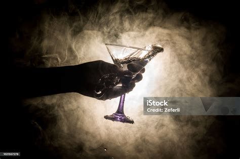 마티니 칵테일 유리 손에 어두운 톤된 연기 배경 또는 밝아진와 올리브 유리에 화려한 칵테일에 튀는 파티 클럽 엔터테인먼트입니다 혼합된 빛입니다 0명에 대한 스톡 사진 및