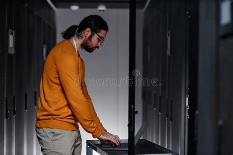 Bearded Network Engineer Using Laptop In Server Room Stock Image