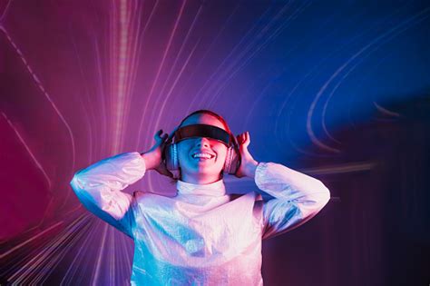 분홍색과 파란색 네온 불빛의 미래 지향적인 선글라스와 헤드폰을 착용한 웃는 춤추는 여성의 초상화 음악 애호가 사일런트 디스코