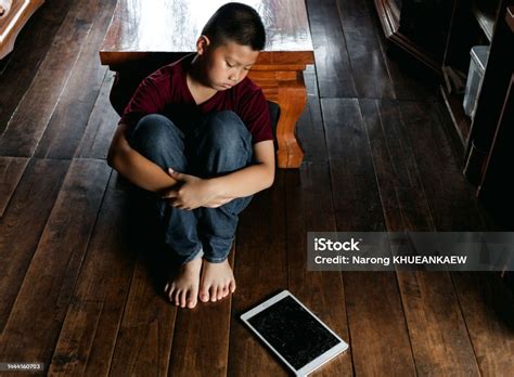 작은 아시아 소년의 초상화 아이 슬픈 얼굴 불행한 아이 앉아 포옹 무릎 그는 바닥에 고장난 태블릿 컴퓨터를 보았다 감정 슬프고 슬픈 얼굴 우울한 아이들 개념 아이에 대한