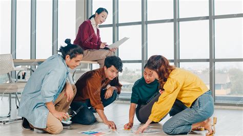 비즈니스 브레인 스토밍 회의 아이디어를 논의하는 캐주얼웨어의 아시아 젊은 창조적 인 사람들의 그룹은 사무실 바닥에 배치 된 모바일 애플리케이션 소프트웨어 디자인 프로젝트