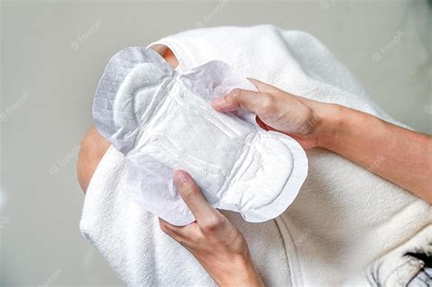 着用前に生理用ナプキンまたは月経パッドを保持しているタオルを着用している女性。使用している女性 Premium写真