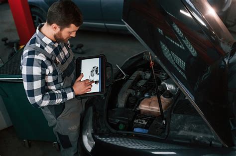 후드가 열린 채 차 근처에 서 있습니다 태블릿을 들고 있습니다 제복을 입은 남자가 자동차 살롱에서 일하고 있다 가까운에 대한 스톡 사진 및 기타 이미지 Istock