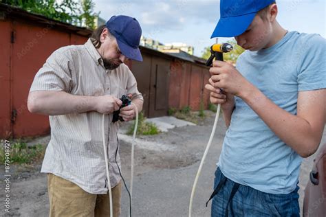 Dad And Teenage Son Work Together On The Street Near The Garage