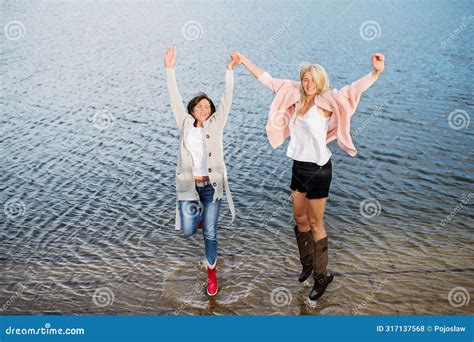 Adult Daughter Spending Time With Her Mother Having Fun Jumping Mom
