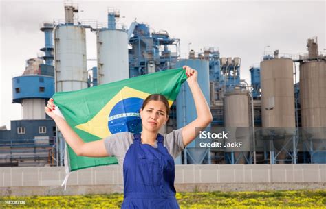 파란 노동자의 작업복을 입은 화가 난 여자가 시골 공장 근처에 서서 브라질의 국기를 들고 있다 20 24세에 대한 스톡 사진 및 기타 이미지 Istock