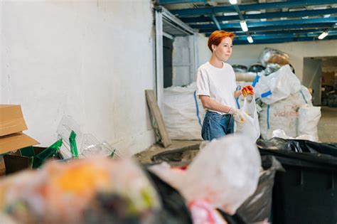 라텍스 장갑을 끼고 현대적인 개인 폐기물 재활용 공장에서 추가 처리를 위해 다양한 폐기물을 분류하는 잠겨 있는 젊은 여성 노동자