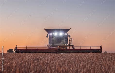 Agriculture Combine Harvester With Headlight Illuminating Wheat Field