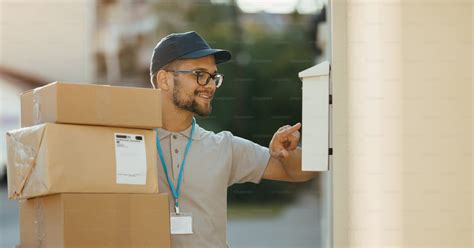 주거 지역에서 소포를 배달하는 동안 고객의 우편함에서 이름을 확인하는 젊은 행복한 택배 사진 Unsplash의 골판지 상자 이미지