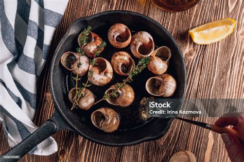 소박한 나무 배경에 철 팬에 허브 버터와 부르고뉴 에스카르고 달팽이 맨 위 보기 에스카르고에 대한 스톡 사진 및 기타 이미지