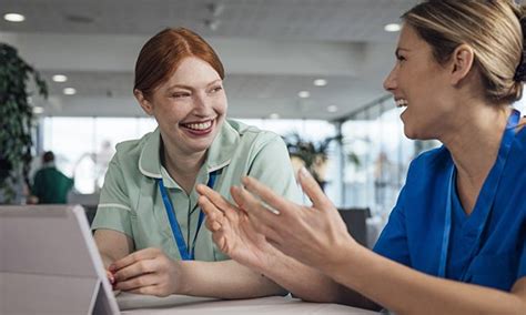 Nmc Revalidation For Nurses Two Nurse Colleagues Laugh Together While Having A Discussion A