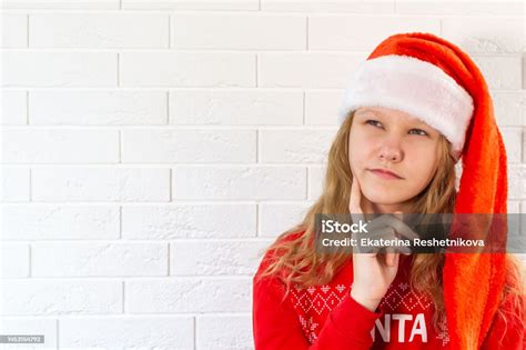 겨울 방학을 축하하는 십대의 재미있는 사진 꿈꾸는 모습 빈 공간 가족 파티를 생각하다 턱에 손 산타 모자의 크리스마스 개념 빨간색 배경색 12 13세에 대한 스톡 사진 및