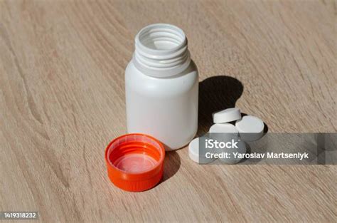 알약을위한 플라스틱 항아리 주황색 뚜껑이있는 흰색 항아리 멸균 용기가 테이블 위에 서 있습니다 감기약 제약 활성 약용 물질이있는