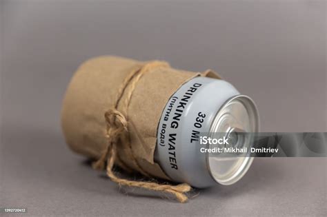 회색 배경 앞에서 물을 마시는 원통형 캔 갈색 종이에 싸인 깡통에 담수 매듭에 묶인 문자열입니다 액체의 부피 330 Ml 0명에 대한 스톡 사진 및 기타 이미지 Istock
