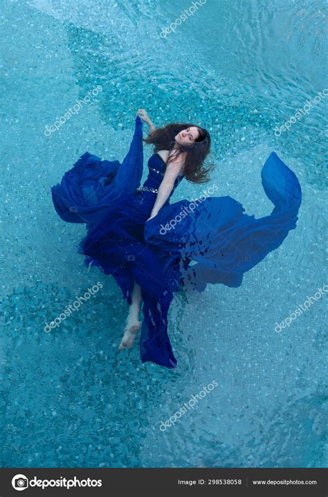Beautiful Young Woman In Blue Evening Dress Floating Weightlessly