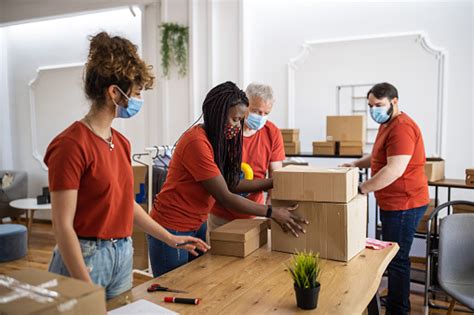 코로나바이러스 전염병 중 배달을 위한 기부 상자를 준비하는 보호 얼굴 마스크를 가진 다민족 자원 봉사자 그룹 20 24세에 대한 스톡 사진 및 기타 이미지 Istock