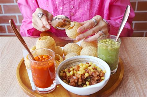 다양한 종류의 맛을 낸 디핑 워터와 함께 제공되는 인도 스낵인 Pani Puri의 속이 빈 껍질을 깨는 여성 Golgappa에 대한 스톡 사진 및 기타 이미지 Istock