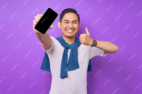 Premium Photo Cheerful Young Asian Man Demonstrating Smartphone With