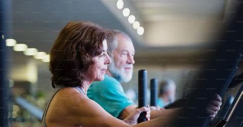 Beautiful Fit Senior Couple In Sports Clothing In Gym Doing Cardio