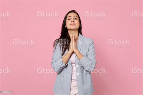 함께 손을 잡고와 스튜디오에서 분홍색 파스텔 벽 배경에 고립 기도하는 줄무늬 재킷에 탄 원 젊은 여자의 초상화 사람들은 진심으로