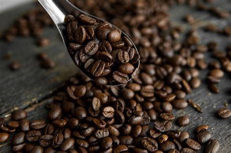 신선한 구운 아라비카 커피 콩을 금속 숟가락에 넣고 나무 테이블에 흩어져 있는 커피 콩 갈색에 대한 스톡 사진 및 기타 이미지 갈색 구이 뜨거운 음료 Istock