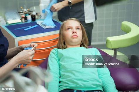 치과 의사 사무실의 의자에 앉아있는 작은 무서운 소녀 아이 발치 치아 치료를 두려워하는 아이는 입을 벌리고 검사합니다 치과 검진 뒤로 젖힌 자세 치과 용 장갑 6 7 살에