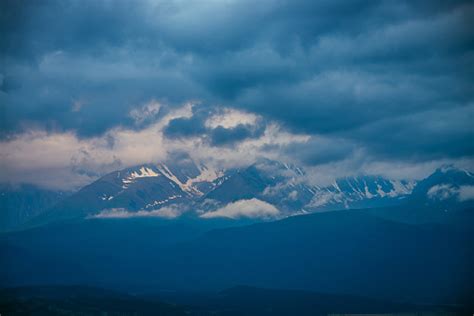 낮은 구름과 일몰 흐린 하늘에 큰 눈 덮인 산과 분위기 산 풍경 푸른 흰색 색상의 낮은 구름에서 높은 산능선에 큰 빙하와 멋진