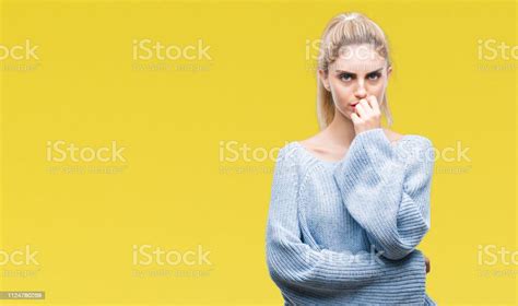 젊은 아름 다운 금발 및 파란 눈 여자는 스트레스와 입 물고 손톱에 손으로 긴장 찾고 고립 된 배경 위에 겨울 스웨터를 입고 불안 문제 감정에 대한 스톡 사진 및 기타