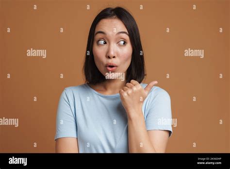 Young Asian Woman Expressing Surprise And Pointing Finger Aside