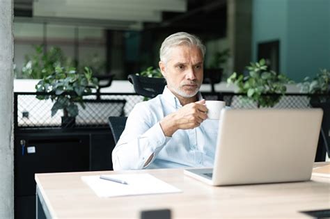 비즈니스 초상화 사무실에 앉아서 노트북 컴퓨터로 작업하고 커피를 마시는 사업가 40 49세에 대한 스톡 사진 및 기타 이미지 40 49세 50 54세 50 59세