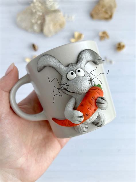a hand holding a coffee mug with a drawing of a bunny and carrot on it