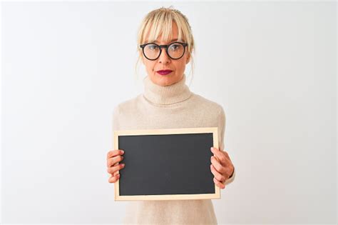 고립된 흰색 배경 위에 칠판을 들고 안경을 쓰고 있는 중년 여성이 스마트한 얼굴에 자신감 있는 표정을 지니고 있습니다 감정에 대한 스톡 사진 및 기타 이미지 Istock