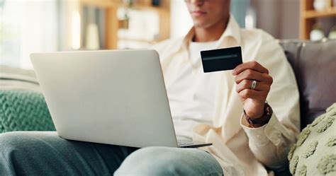 신용 카드 노트북 및 소파에 있는 남자의 손은 온라인 쇼핑 인터넷 뱅킹 및 가정에서 지불을 위한 것입니다 전자 상거래 핀테크 및 컴퓨터 사용자를위한 웹 사이트 판매 구매