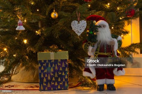 빨간 코트와 모자를 쓴 산타클로스가 선물을 들고 크리스마스 트리 옆에 서 있습니다 12월에 대한 스톡 사진 및 기타 이미지 12월 겨울 계절 Istock