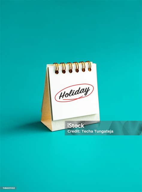 휴일 여름과 휴가 개념입니다 휴일의 편안한 서예 글꼴 아쿠아 블루 배경 세로 및 미니멀 스타일에 작은 스탠딩 책상 달력 페이지에 손으로 쓴 빨간색 둥근 표시 달력에 대한