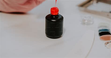 빨간 액체 한 병을 들고 장갑을 낀 손 사진 Unsplash의 손톱 페인팅 이미지