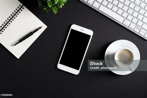 블랙 오피스 데스크 테이블 상단 보기 빈 화면 모형 컴퓨터 키보드 커피 한 잔 종이 메모장이있는 평면 평신도 스마트 폰 블로거 작업 영역 비즈니스 개념 사무실에 대한 스톡