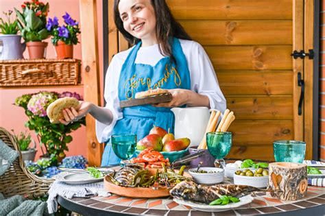 저녁 식사 테이블 근처 그녀의 손에 빵과 파란색 앞치마에 소녀 많은 다른 음식 테이블제공 아늑한 집 갑각류에 대한 스톡 사진 및 기타 이미지 Istock