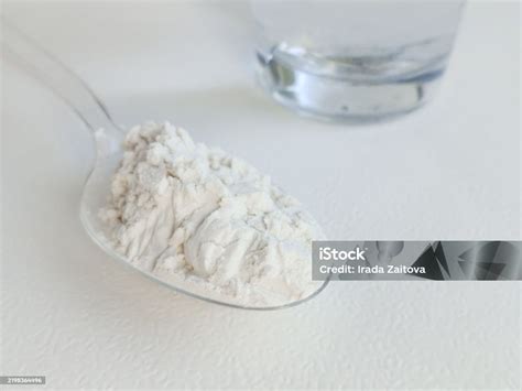 단백질 가루가 든 플라스틱 숟가락이 하얀 탁자 위에 놓여 있고 배경에는 물 한 컵이 놓여 있다 건조 단백질 파우더 근육량의 증가 식품 첨가물 0명에 대한 스톡 사진 및 기타