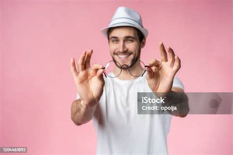 쾌활한 힙스터 남자는 행복하게 미소 핑크 스튜디오 배경을 통해 자연스럽게 고립 된 옷을 입고 흥분 한 표정을 가지고있다 사람 청소년 감정 개념 개념에 대한 스톡 사진 및