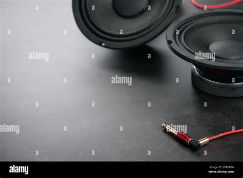 Close Up Red Auxauxiliary Cable With Male Jack With Speaker In The Background Cable For