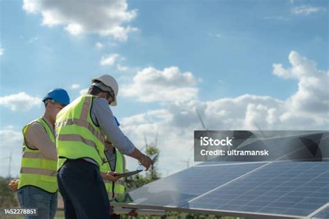 엔지니어 는 전자 장치로 태양 전지 패널 또는 태양광 전지의 건설을 검사합니다 녹색 전력의 산업 재생 에너지 타워 지붕에서 일하는 공장 노동자 3 명에 대한 스톡 사진 및