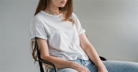 다리를 꼬고 의자에 앉아 있는 여자 사진 Unsplash의 화이트 티셔츠 이미지