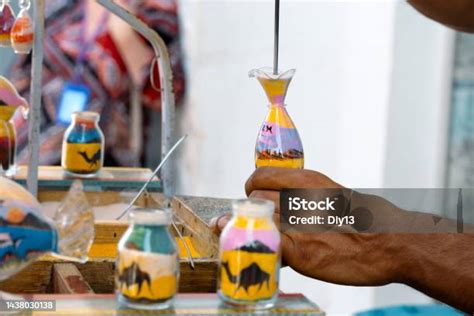 한 남자가 유리 용기에 여러 가지 빛깔의 모래를 붓습니다 장인은 색깔의 모래를 사용하여 병에 기념품을 만듭니다 Experimental Advanced