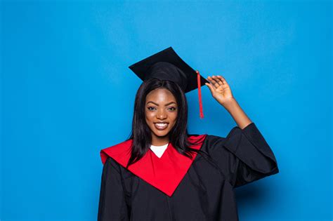 졸업장을 들고 파란색 졸업 가운을 입고 아름다운 아프리카 여성은 파란색 배경에 고립 되어 매우 행복하고 흥분 교육에 대한 스톡